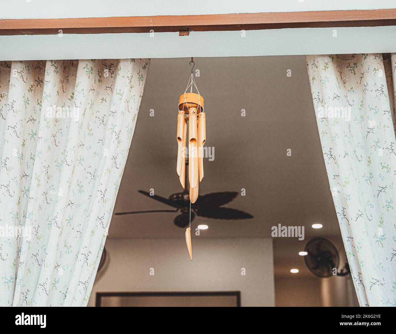 A low-angle of dark wind chimes bamboo with curtains on both sides and ...