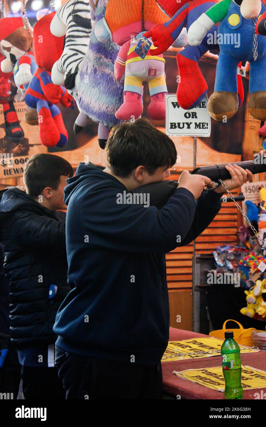 Kid aiming down the barrel of a fairground gun Under toys hes trying to ...