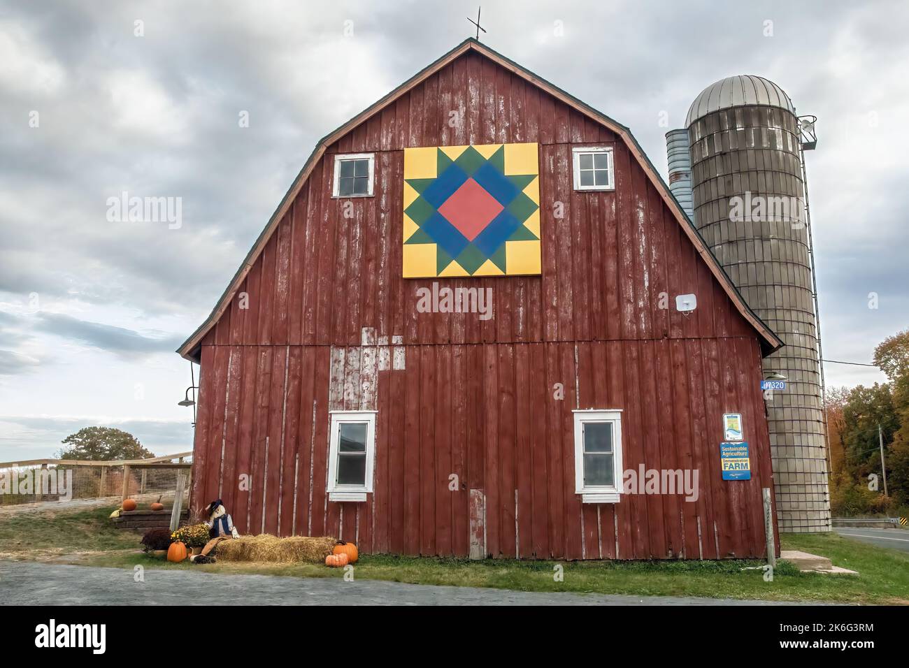 Rustic red barn and silo with a pretty barn quilt on it on a cloudy ...