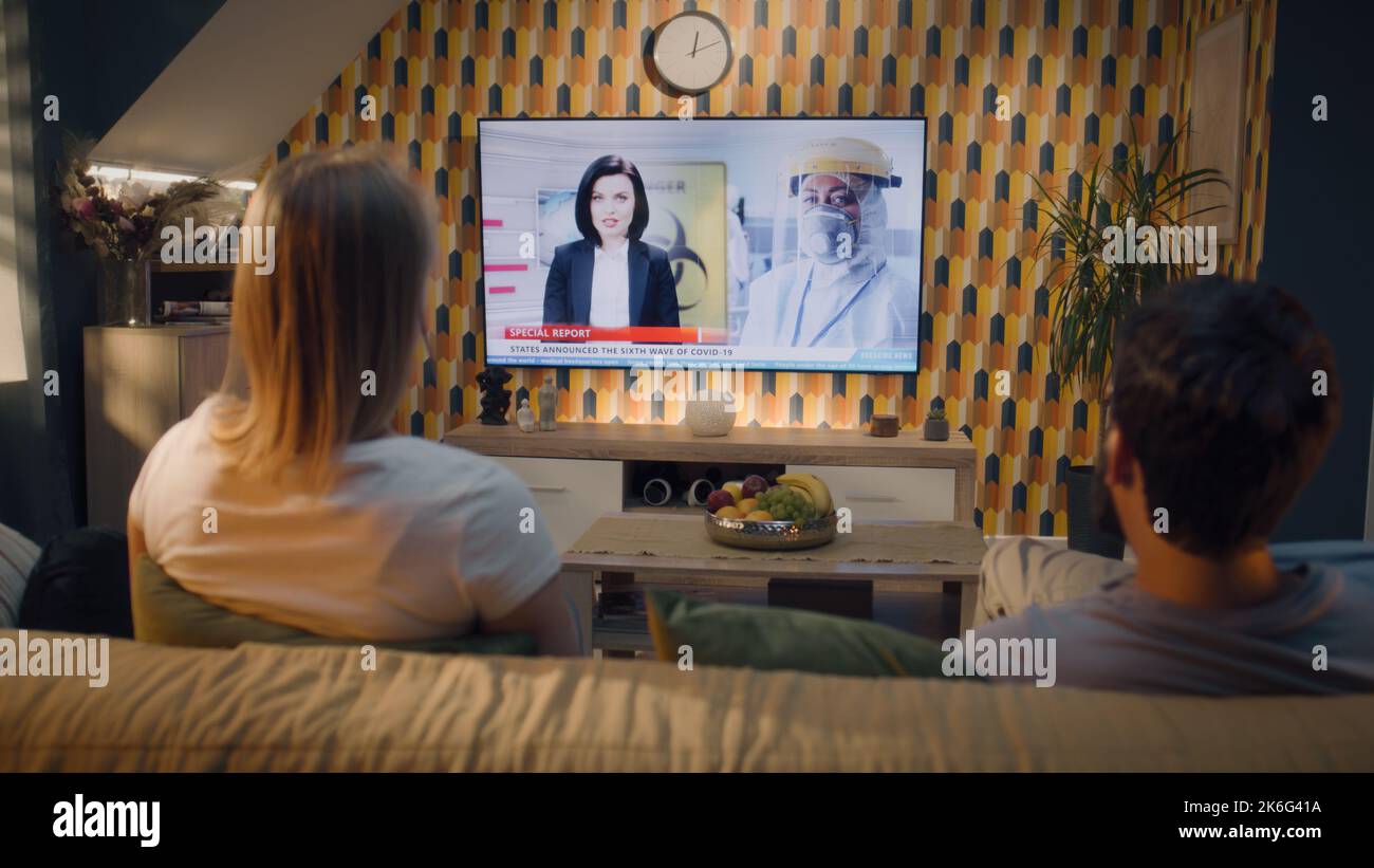 Couple sitting on sofa together in living room with modern interior ...