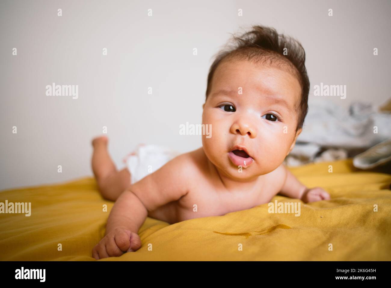 Little baby girl crawling in bed at home with happy face on yellow ...