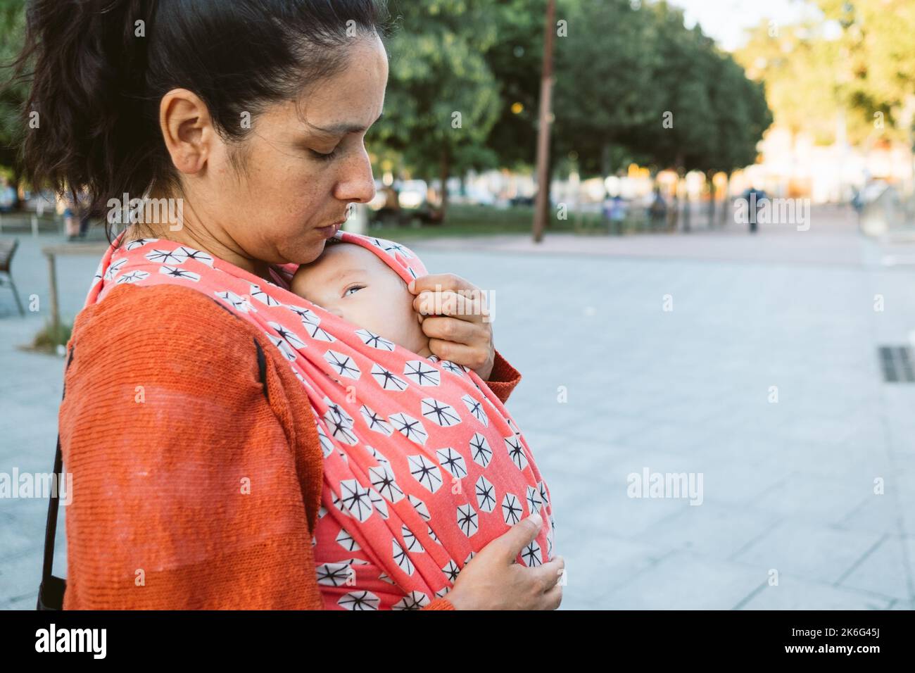 Young mum babywearing in the city. baby in wrap carrier during porting ...