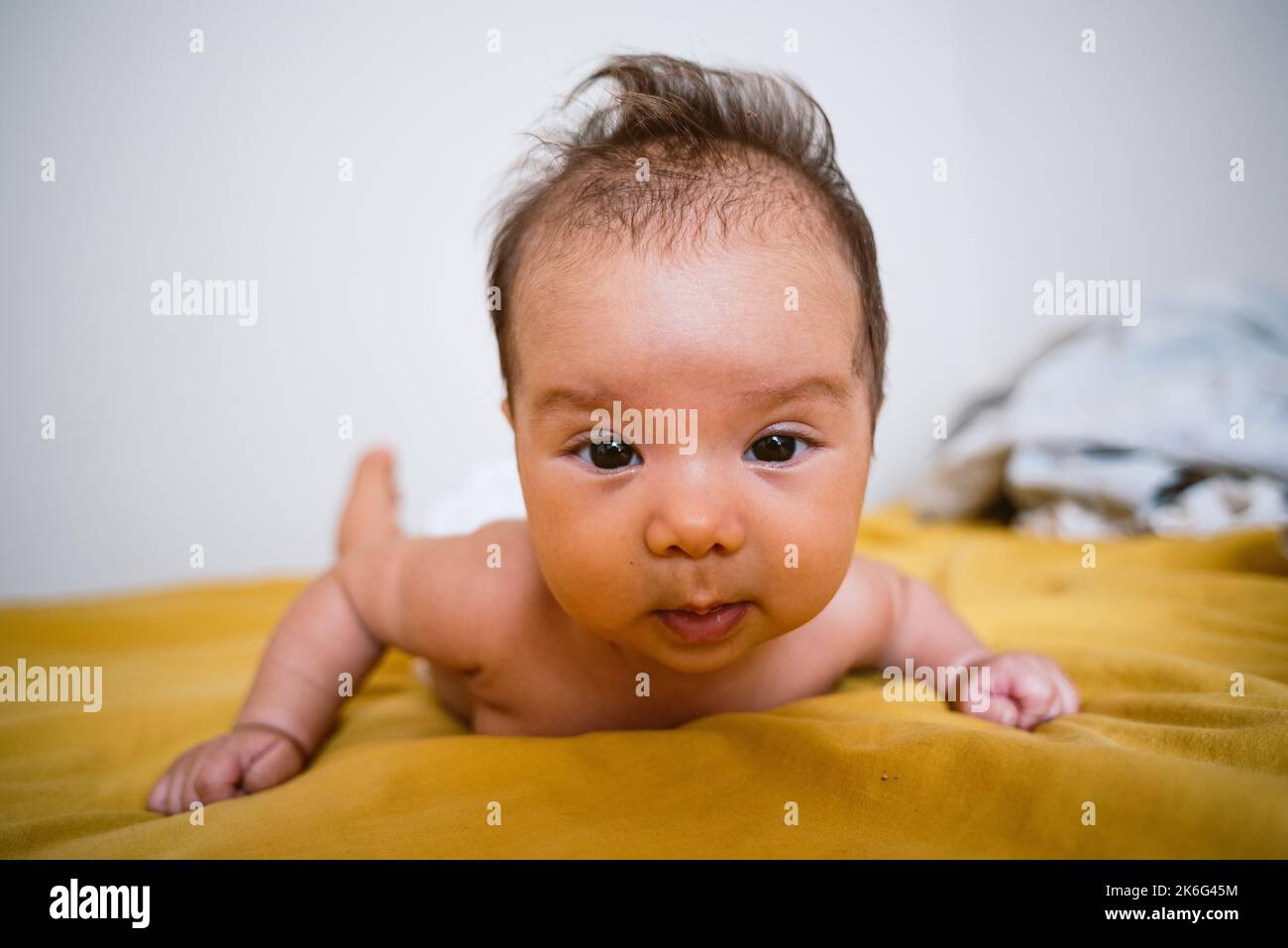 Little baby girl crawling in bed at home with happy face on yellow ...