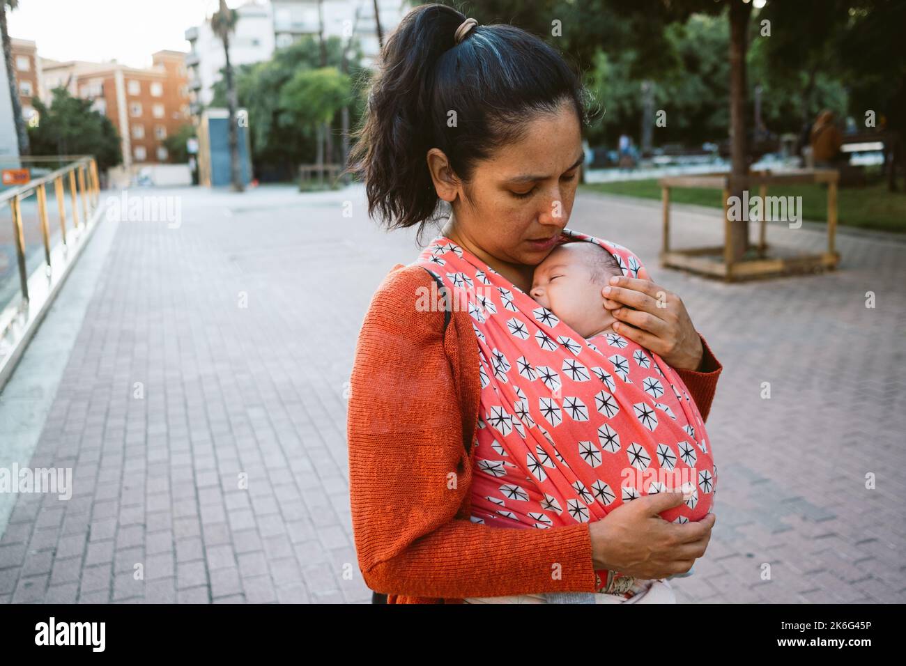 Young mum babywearing in the city. baby in wrap carrier during porting ...