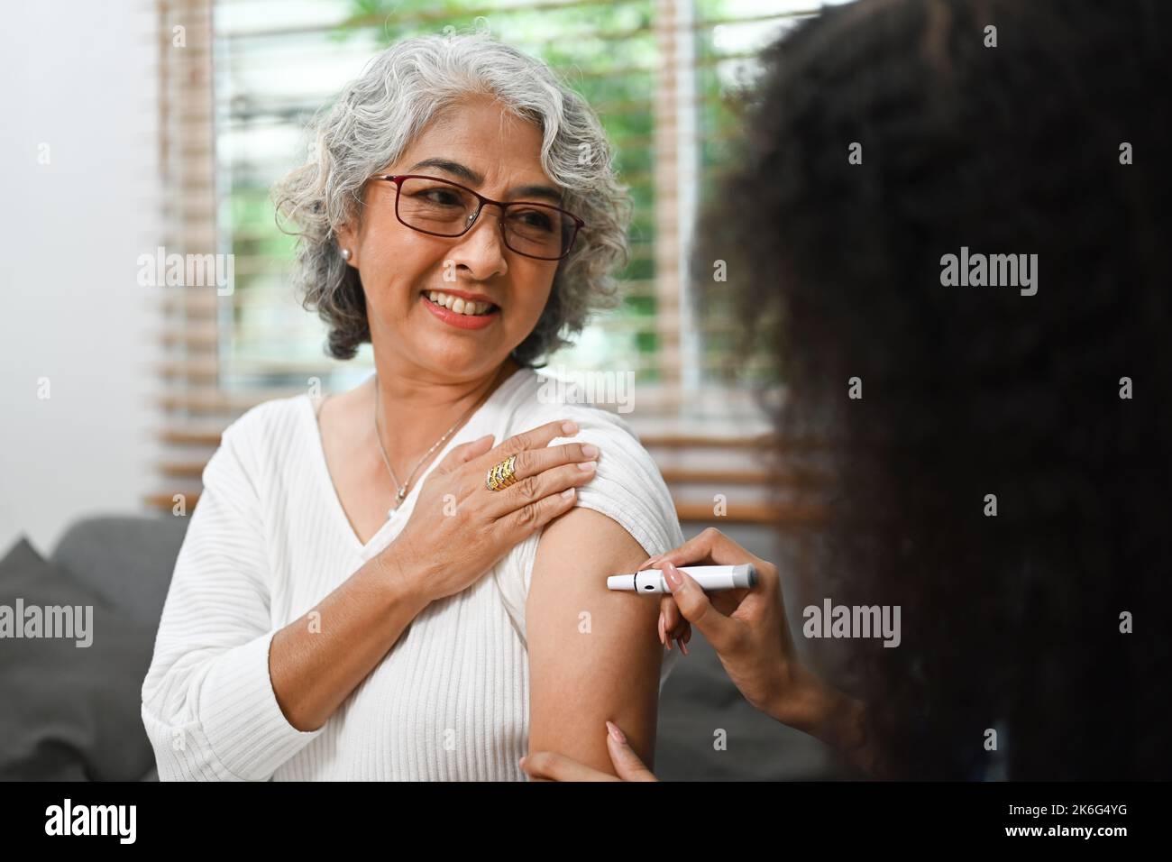 Nurse injecting insulin into upper arm of diabetic elderly patient ...