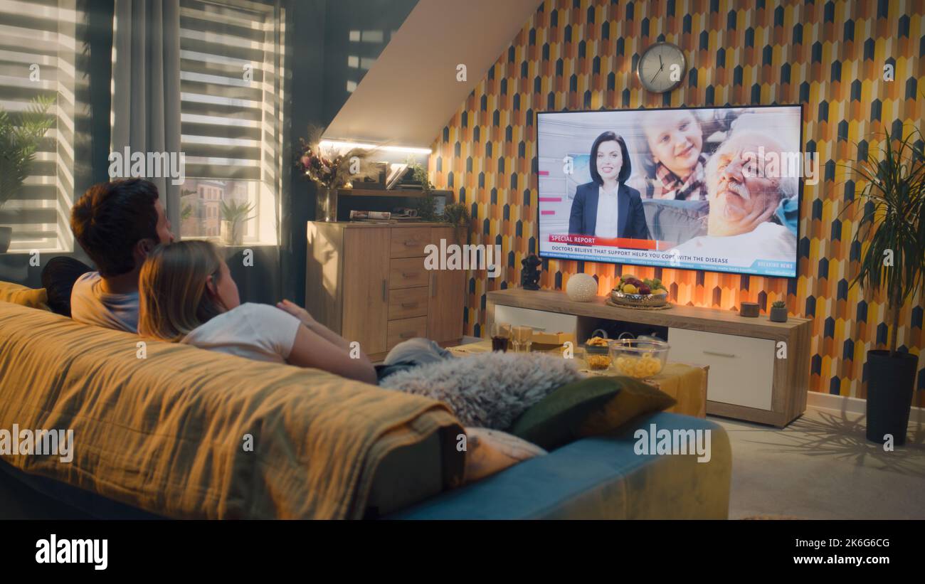 Couple on couch in living room with modern interior, talking, watching ...