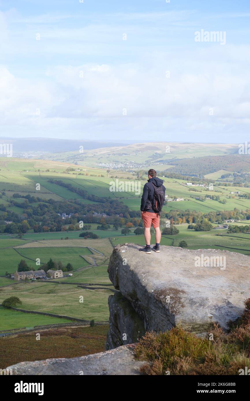 Earl Crag, North Yorkshire, UK. Man standing on rocky outcrop taking in ...