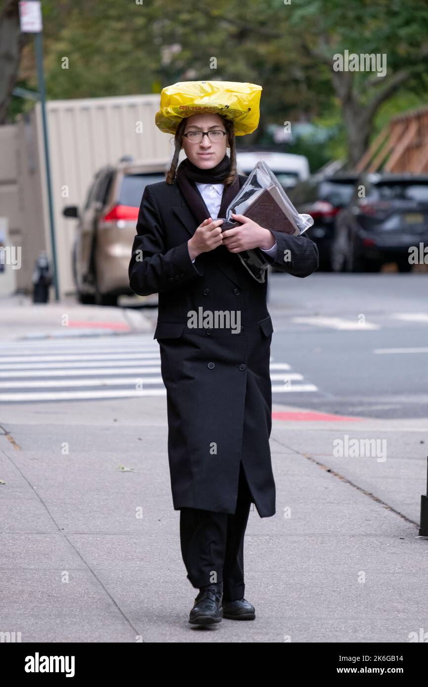 On a drizzly autumn day a Hasidic Jew protects his hat wearing and ...