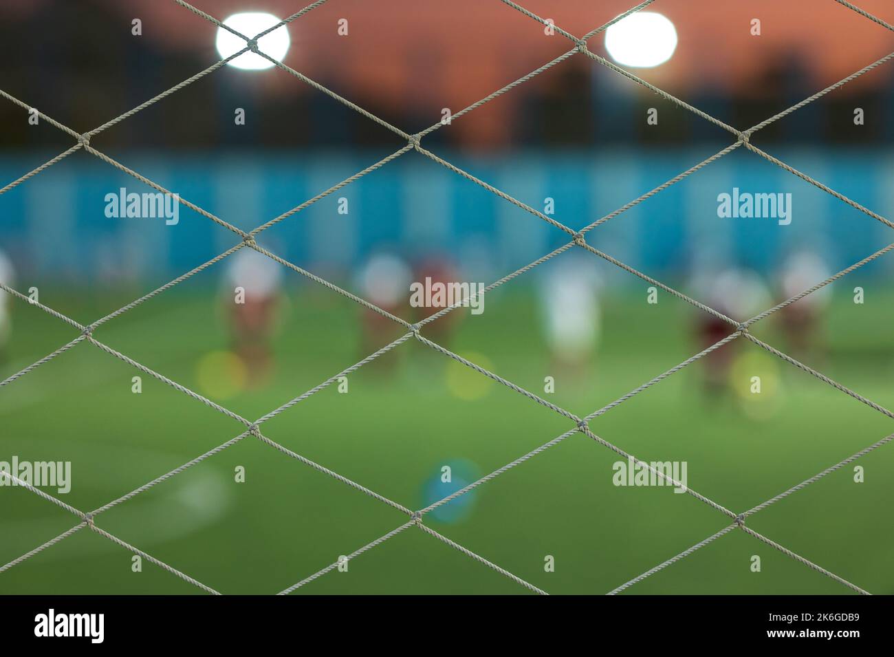 A blurred football net background and players behind the goal with ...