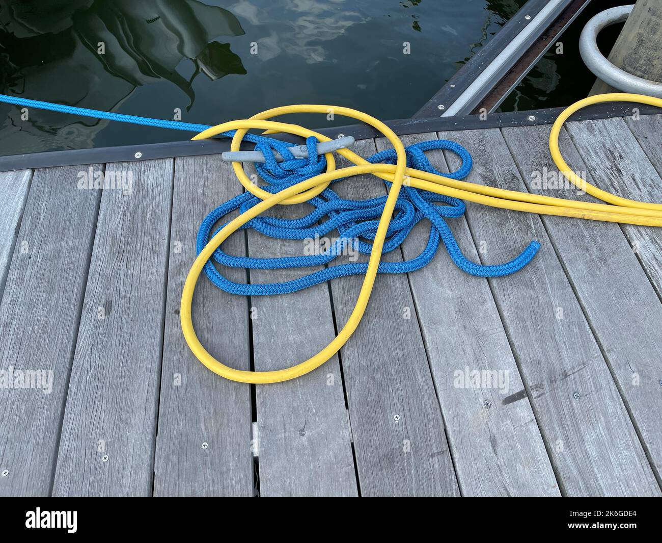 A closeup of a blue rope moor knot on the wooden boating deck with ...