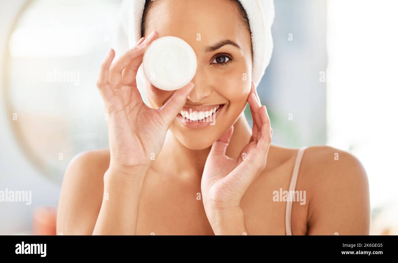 The best eye cream. a young woman applying cream to her face at home ...