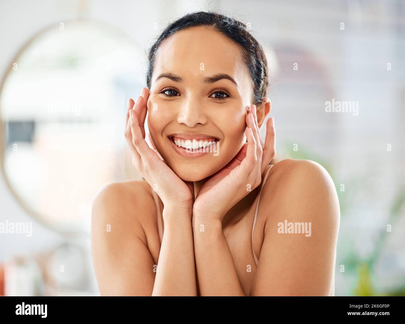 Brighten up your face with a smile. a young woman admiring her skin in ...