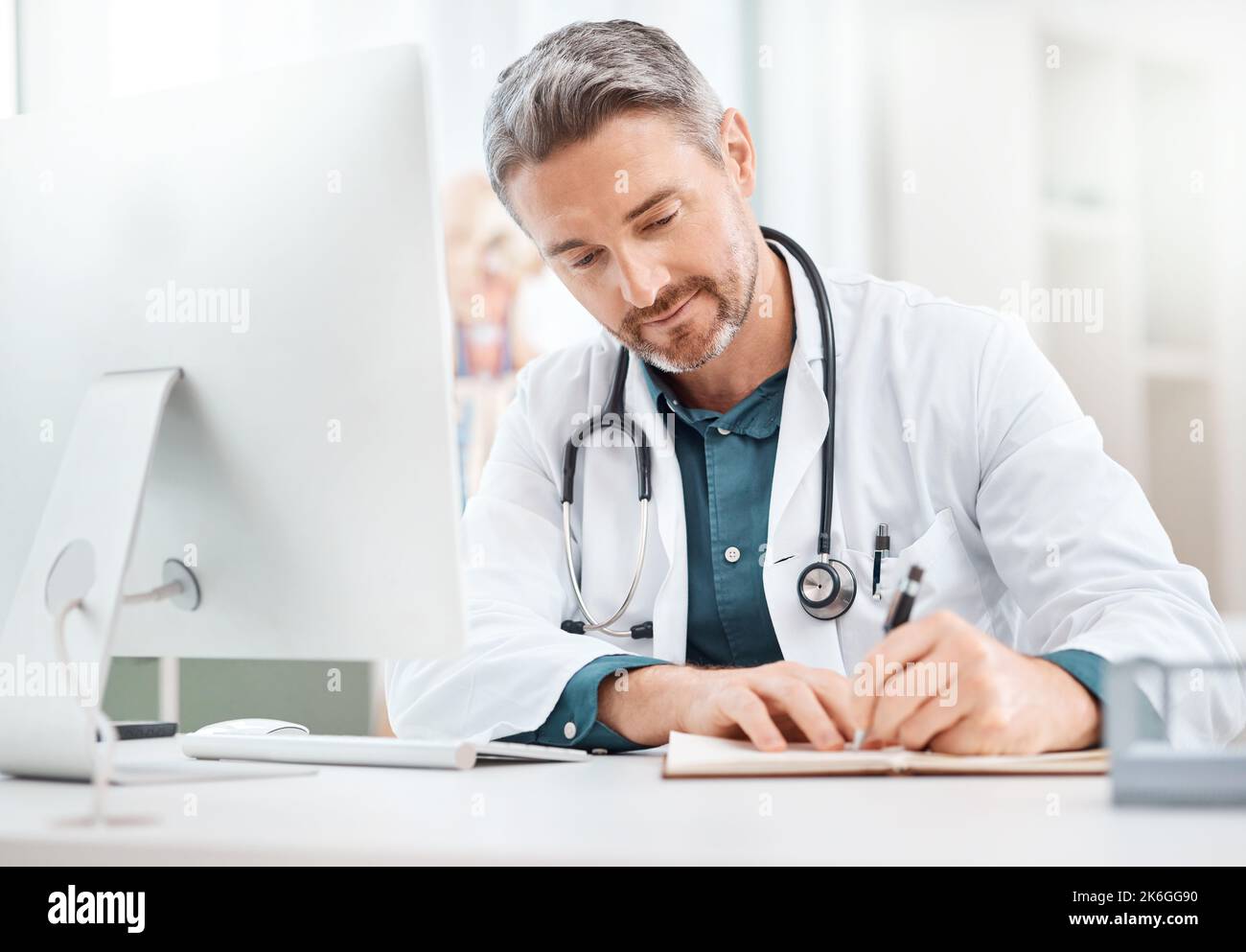 Compiling some new records. a mature doctor writing notes while working ...