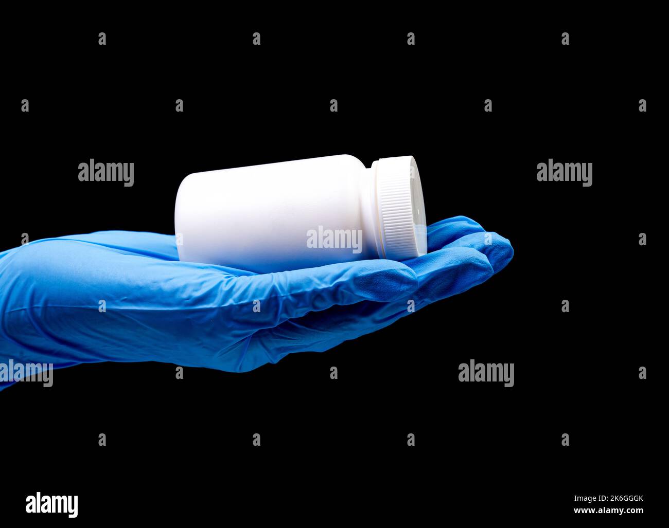 Medical pills in white jar on an isolated black background with ...