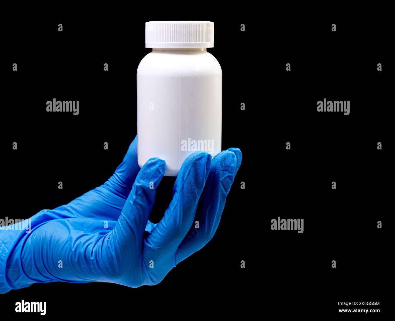 Medical pills in white jar on an isolated black background with ...