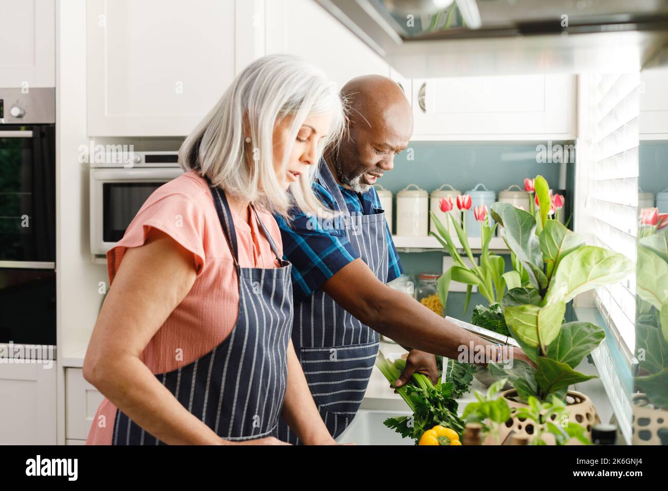 Happy senior diverse couple wearing aprons and cooking in kitchen Stock ...