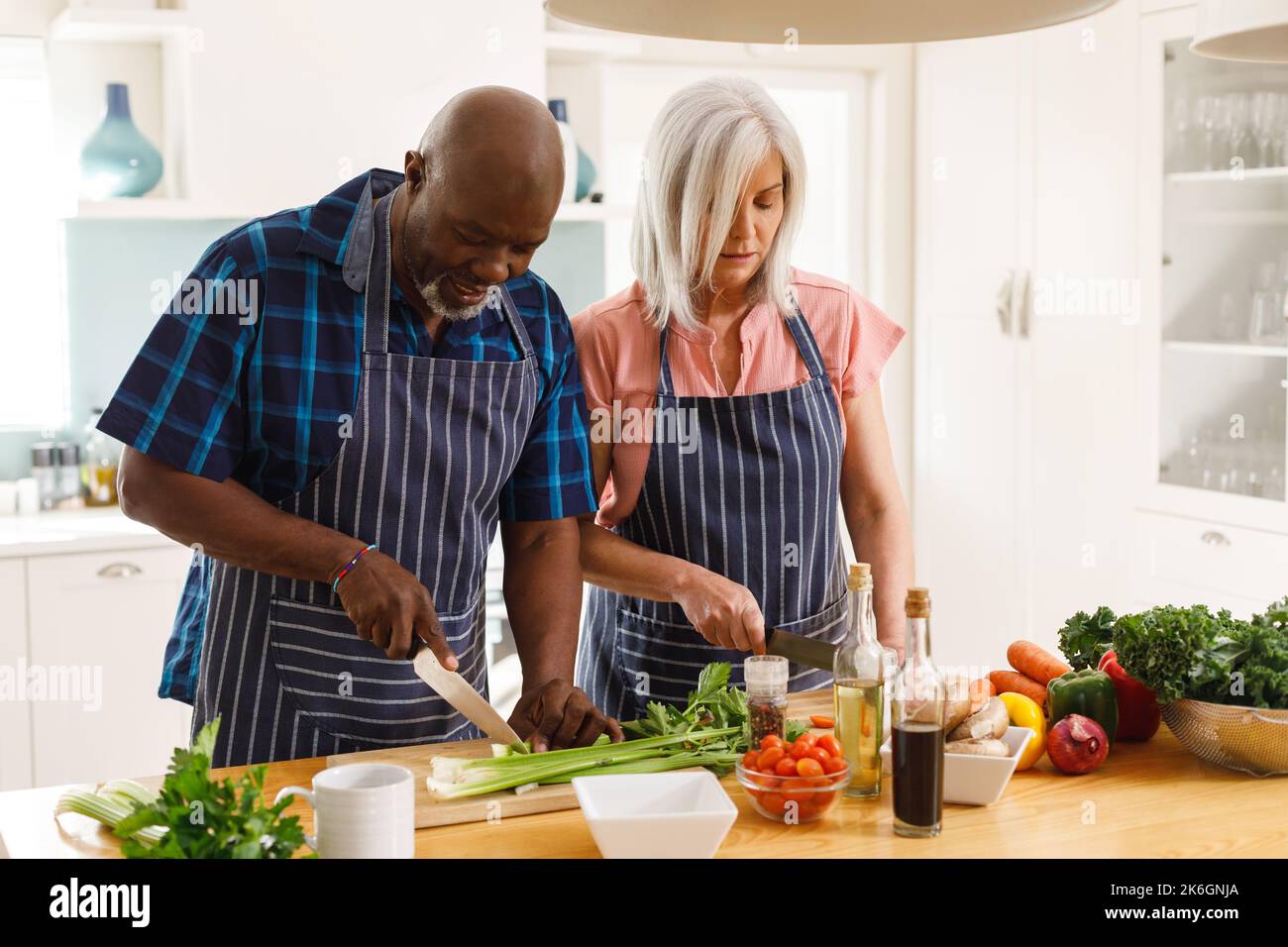 Happy senior diverse couple wearing aprons and cooking in kitchen Stock ...