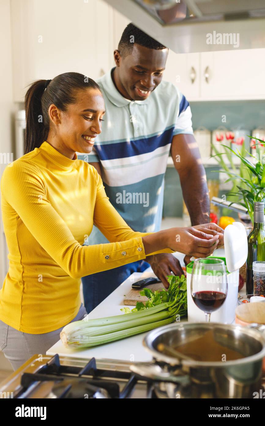 Vertical image of happy diverse couple preparing food together ...