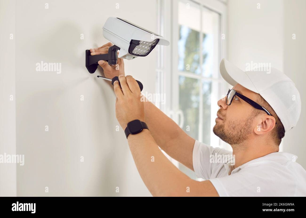 Worker installs security camera with LED light on wall Stock Photo - Alamy