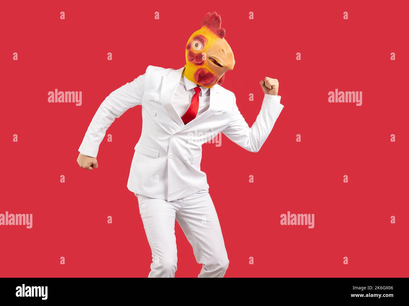 Cheerful funny man in rubber mask of chicken and in white formal suit ...