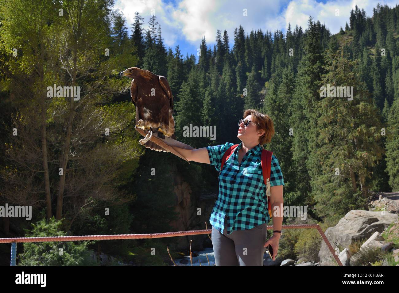 Tourist woman with hunting golden eagle Aquila chrysaetos against ...