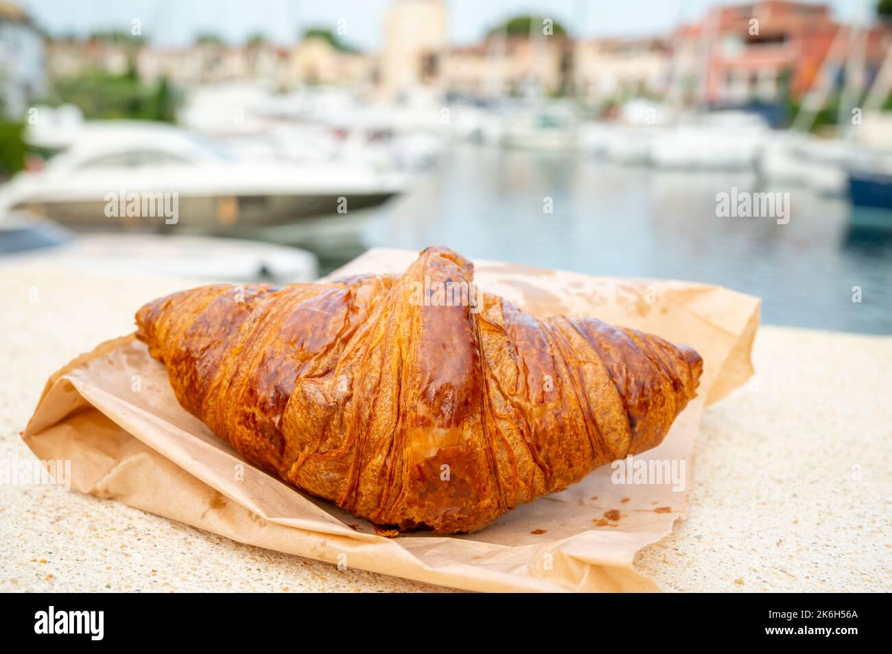 Fresh baked french croissant and boats of Port Grimaud on background ...