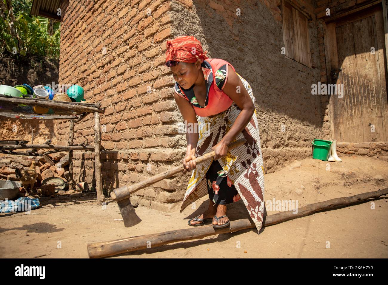 An African woman chops firewood before cooking at her home in Kasese ...