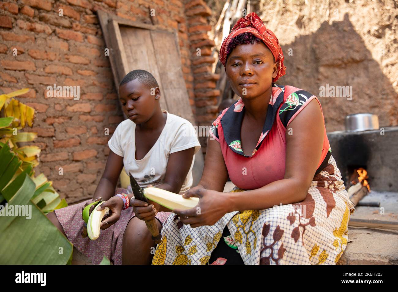 A young woman and her mother peel starchy bananas, the East African ...