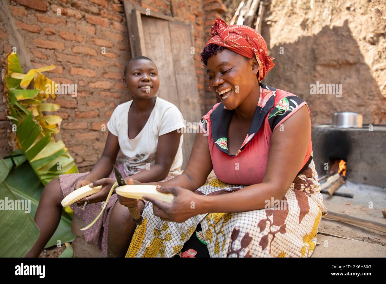A young woman and her mother peel starchy bananas, the East African ...