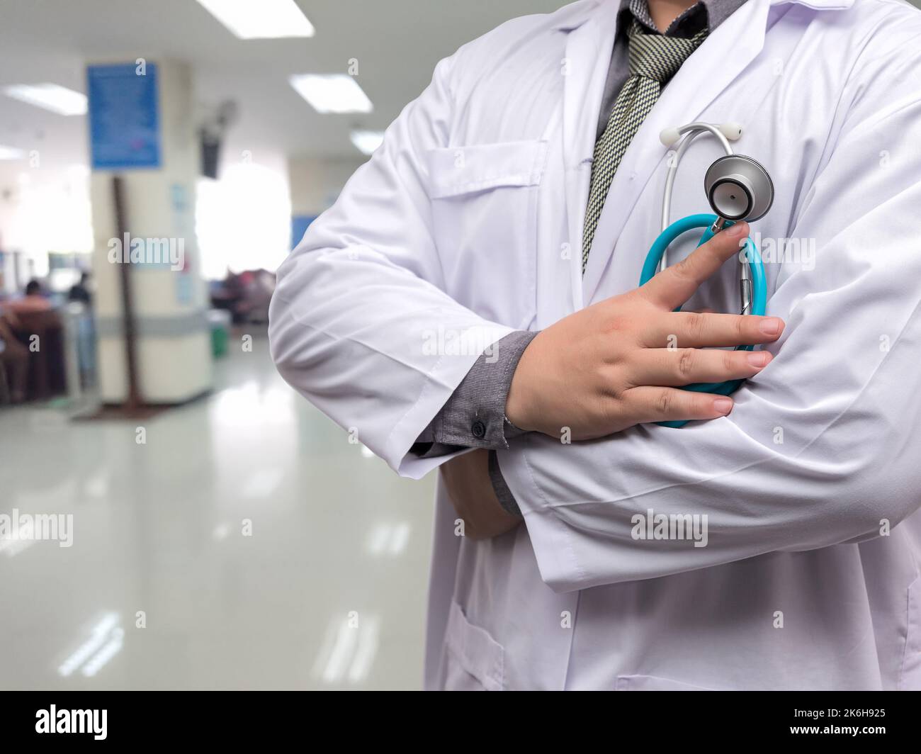 Doctor in gown uniform with stethoscope standing and fold his arms over the chest on OPD ...
