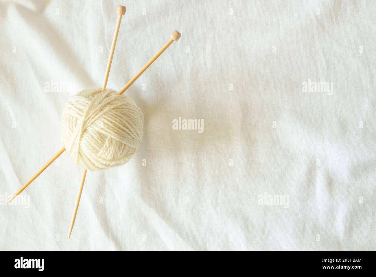 White wool thread ball with wooden bamboo knitting needles on white ...
