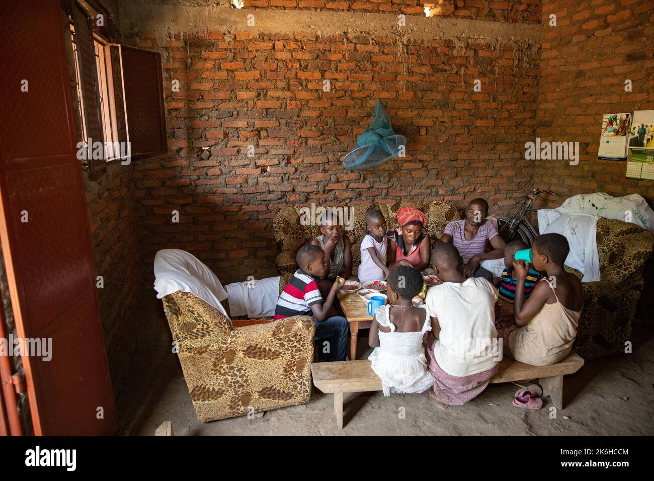 Ugandan family sharing a meal of beans and mashed savory bananas ...