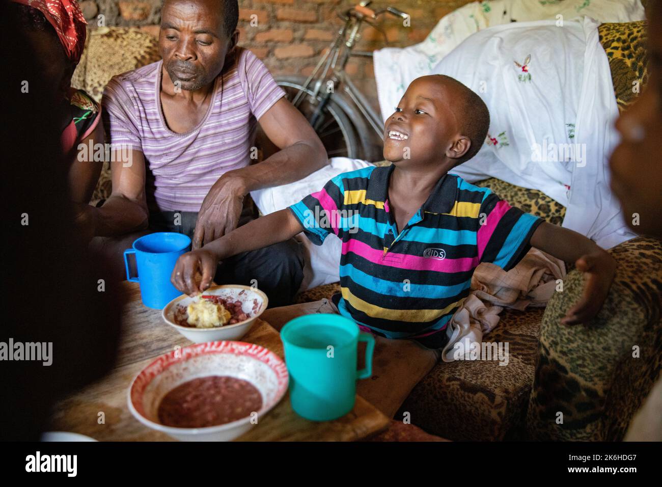 Ugandan family sharing a meal of beans and mashed savory bananas ...
