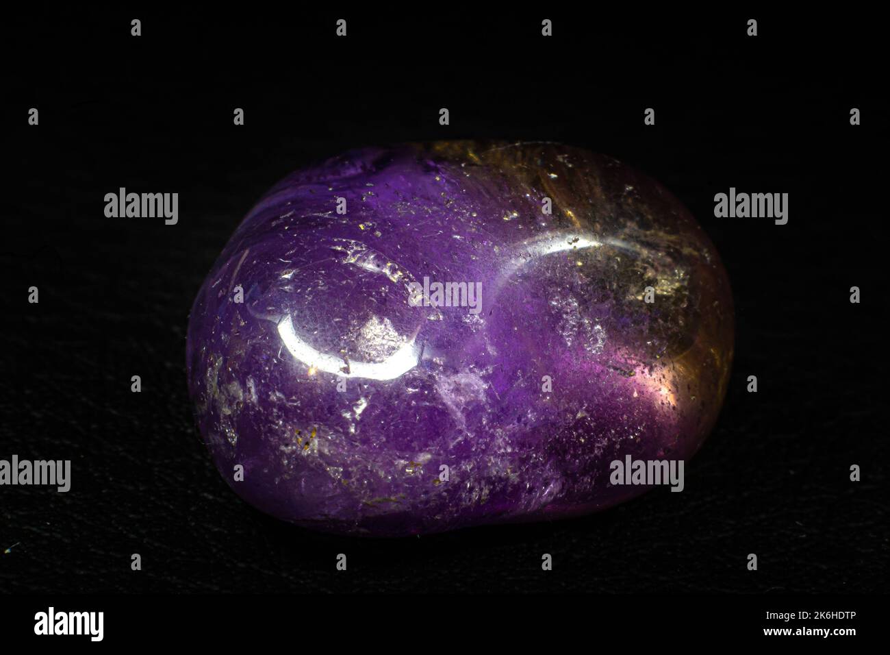 Real tumbled Ametrine stone macro isolated on black surface. Purple ...