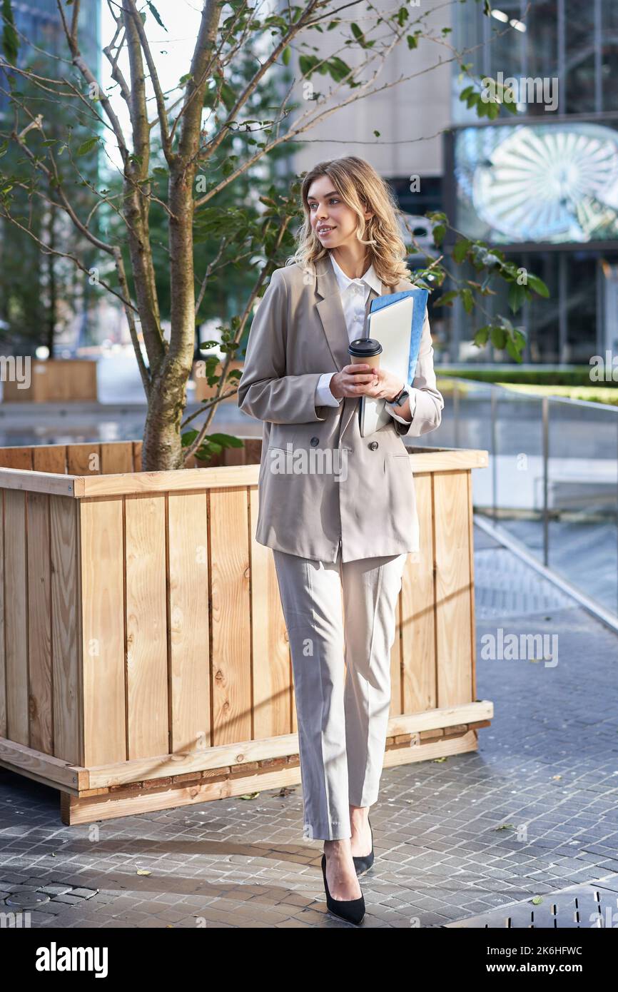 Stylish corporate woman in suit, standing on street with documents ...