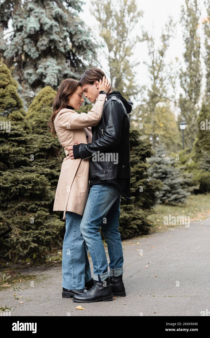 full length of young woman in beige trench coat hugging boyfriend in ...