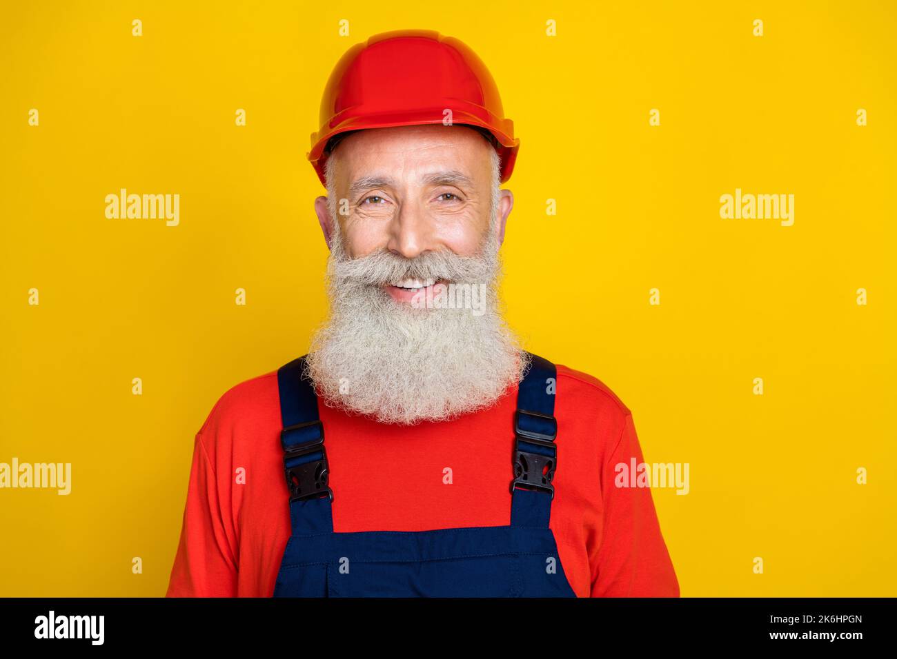 Photo of cheerful funny senior guy dressed uniform overall red hardhat ...