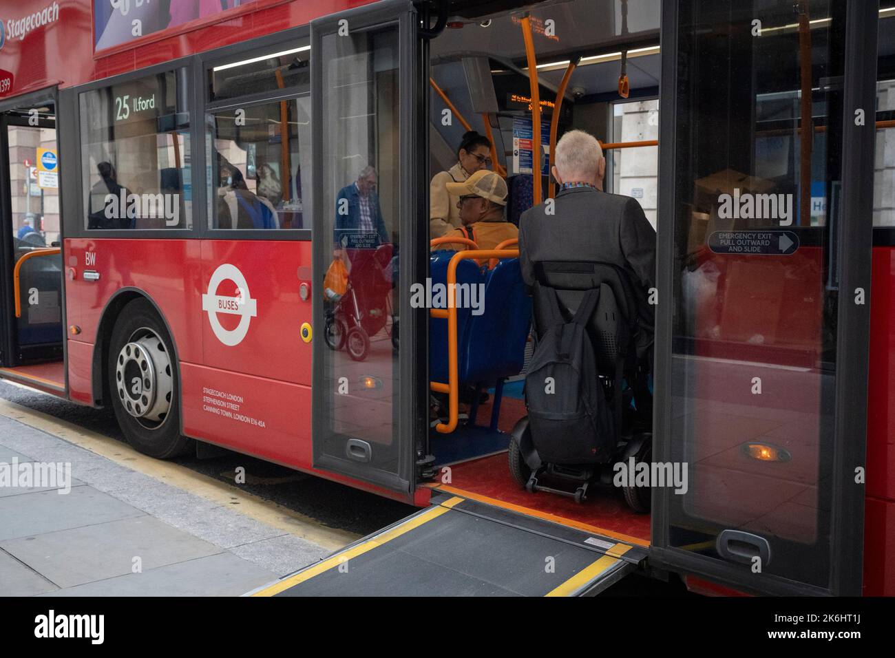 A disabled man on a mobility scooter, boards a London bus using the ...