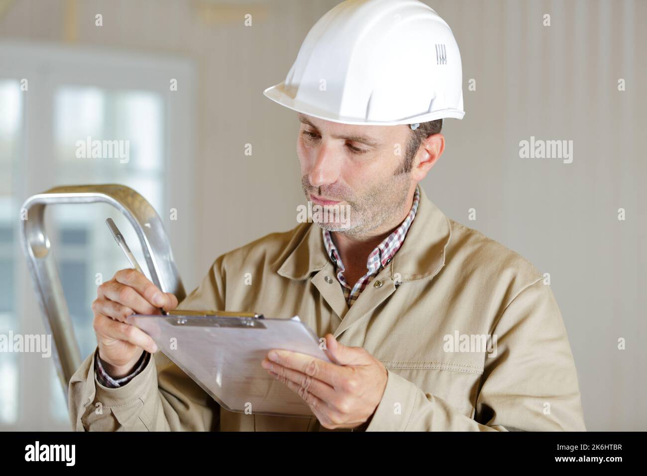portrait of a male builder writing on clipboard Stock Photo - Alamy