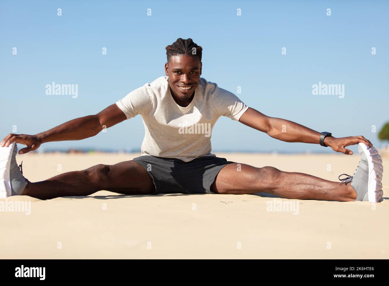 athlete stretching adductor and hamstring after running at the beach ...
