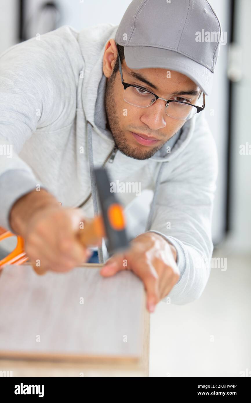 young workman wearing eyeglasses is using a hammer Stock Photo - Alamy
