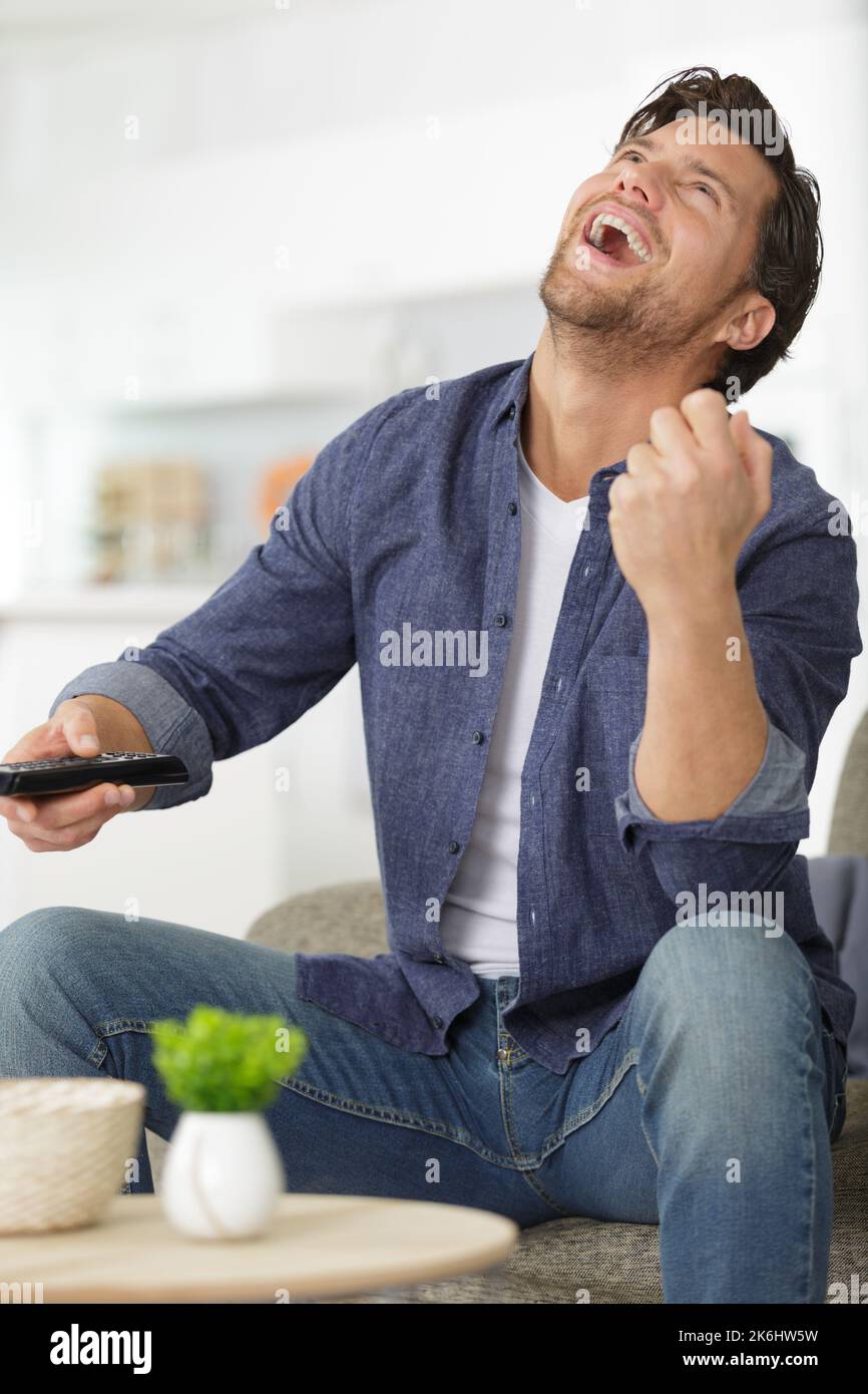 man watching tv making gesture of victory Stock Photo - Alamy