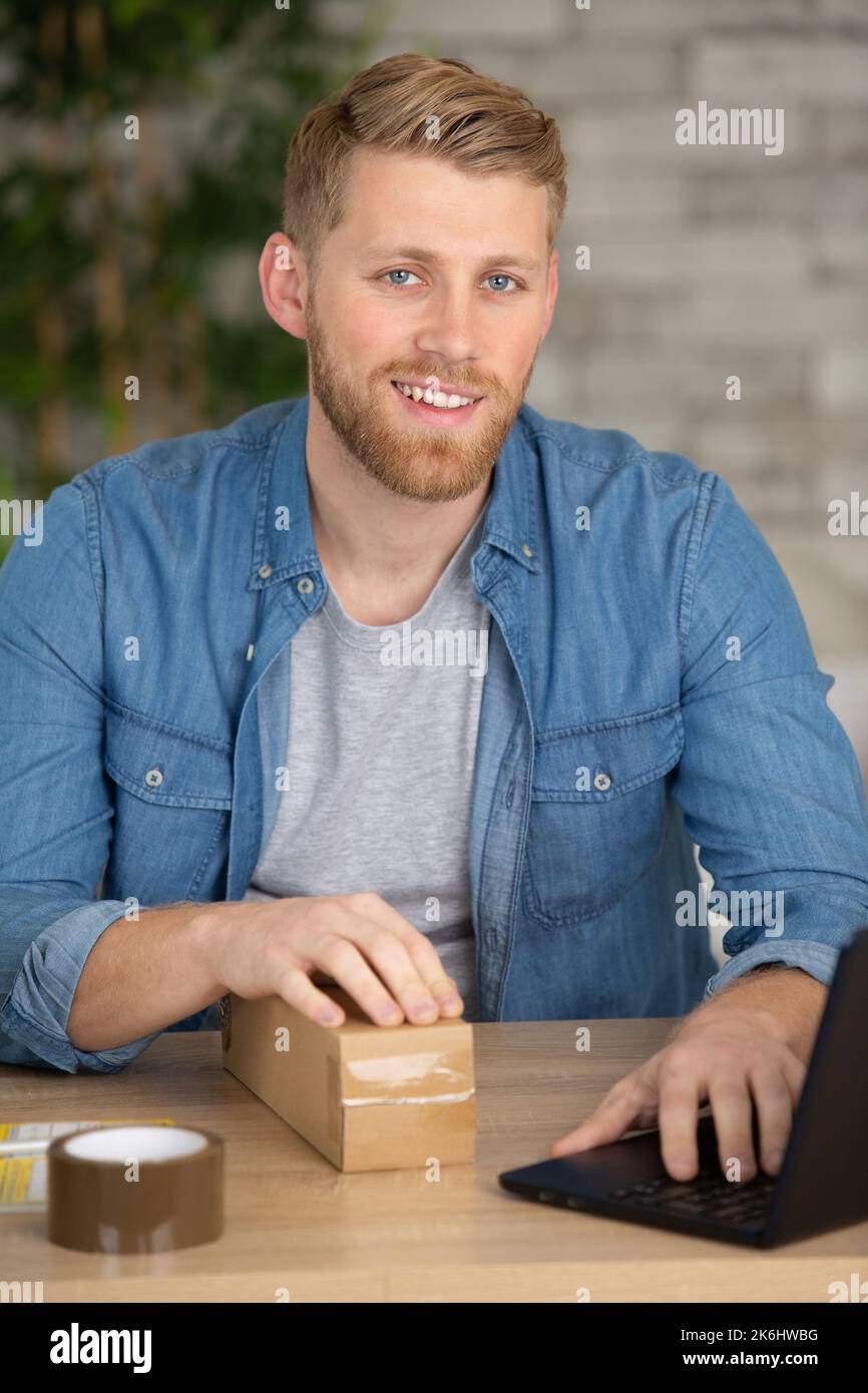 man sat at computer desk with a small parcel Stock Photo - Alamy