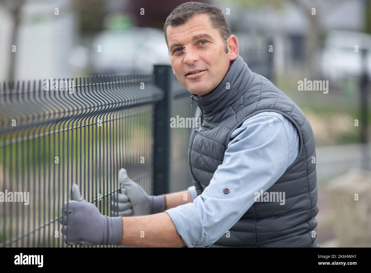 worker installing welded metal mesh fence Stock Photo - Alamy