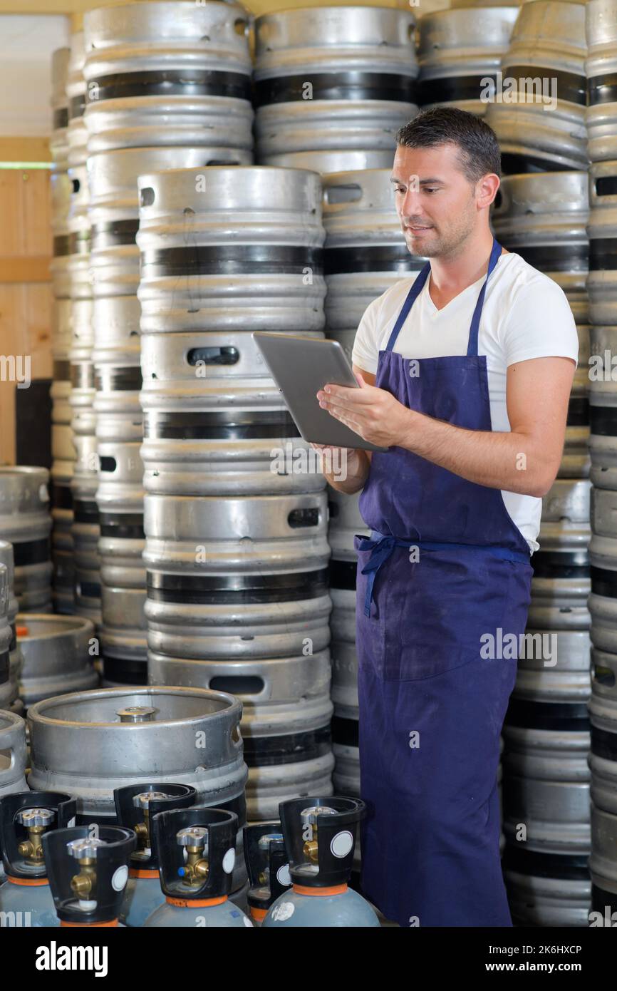 male worker holding digital tablet by barrels of beer Stock Photo - Alamy