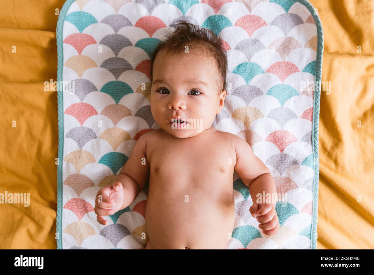 close up of cute smiling latino baby girl in bed with morning light. Waking up in bed. healthy ...
