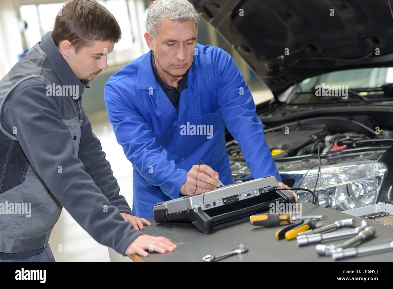 auto mechanic teacher and trainee performing tests at mechanic school ...