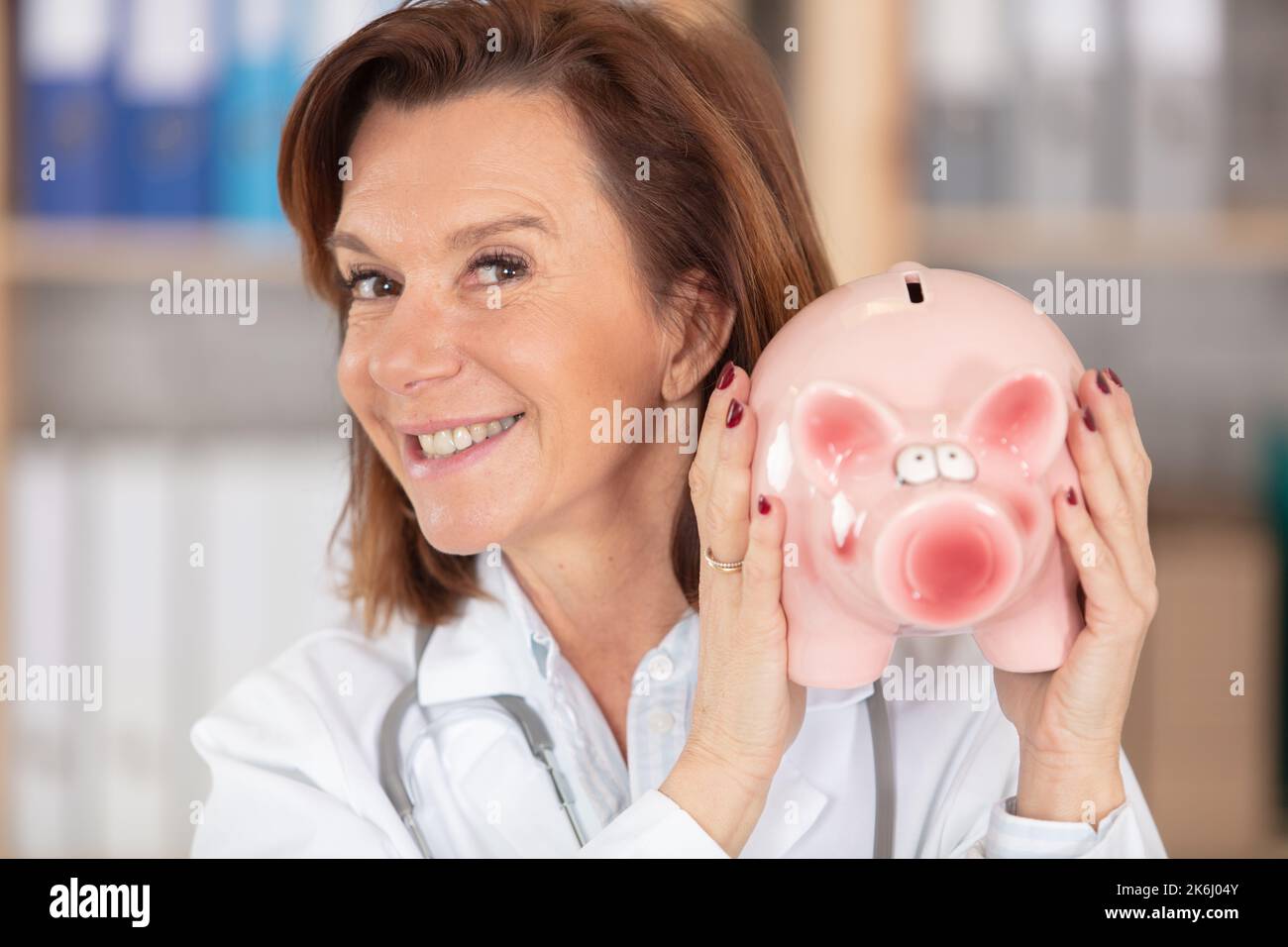 female doctor holding piggy bank Stock Photo - Alamy