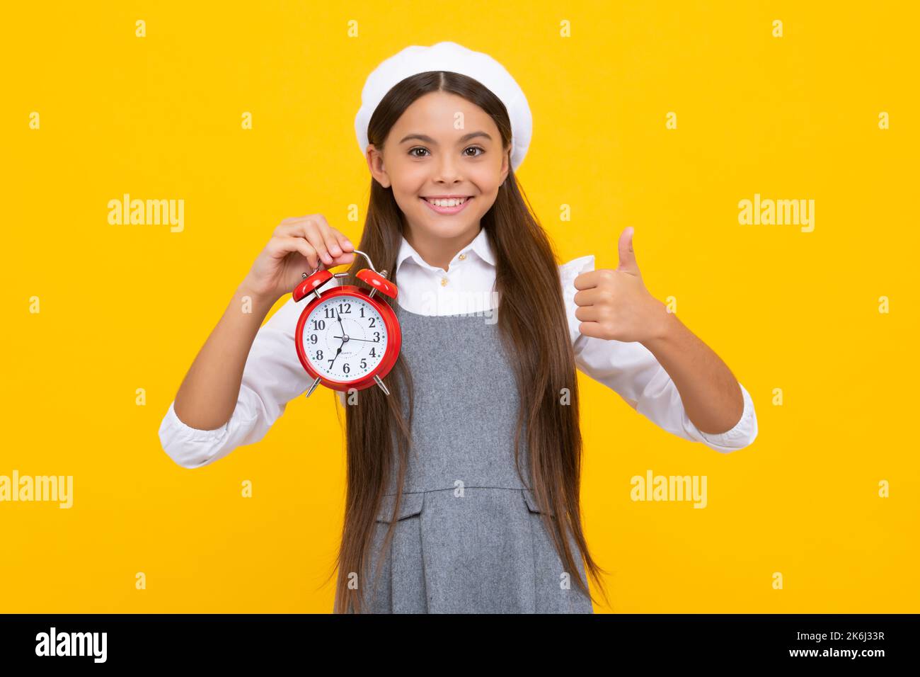 Teenager child hold clock isolated on yellow studio background ...