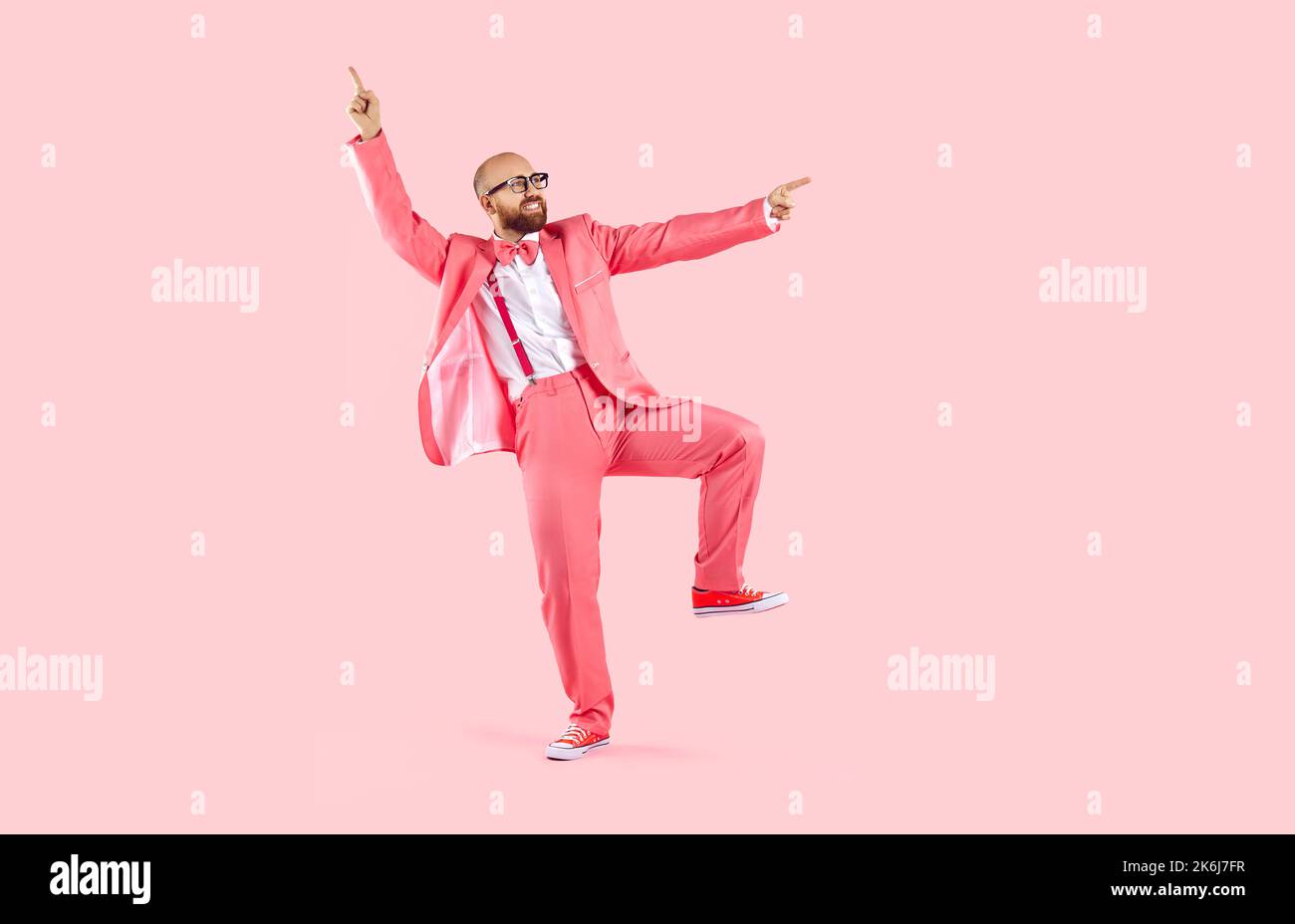 Funny dancer in pink suit, trainers and glasses dancing and having fun ...